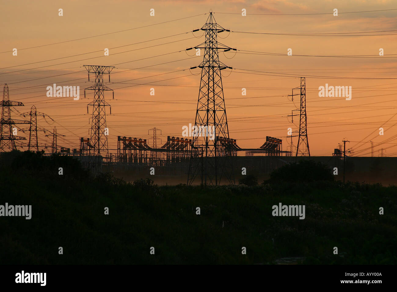 Pylons and power distribution plant against sunset Stock Photo - Alamy
