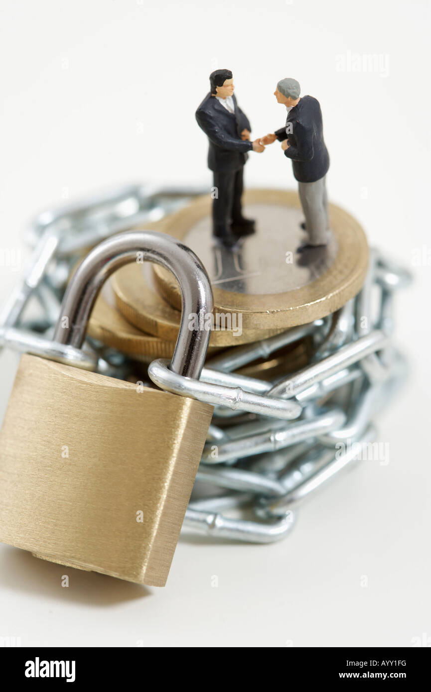 Businessmen figurines shaking hands on a stack of coins wrapped of a ...