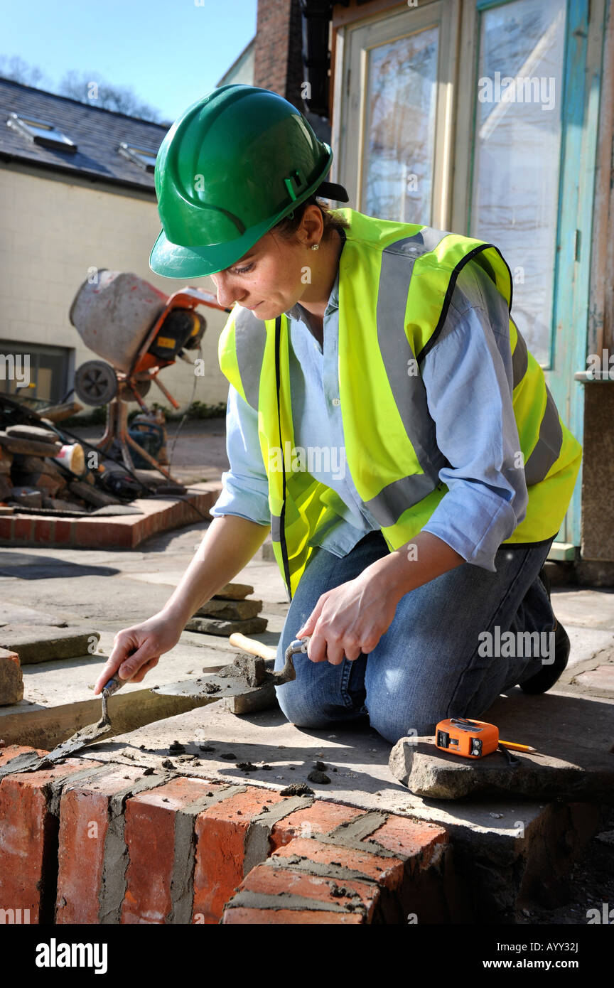 A FEMALE BUILDER POINTING IN THE EGDING BRICKS ON A PATIO UK Stock ...