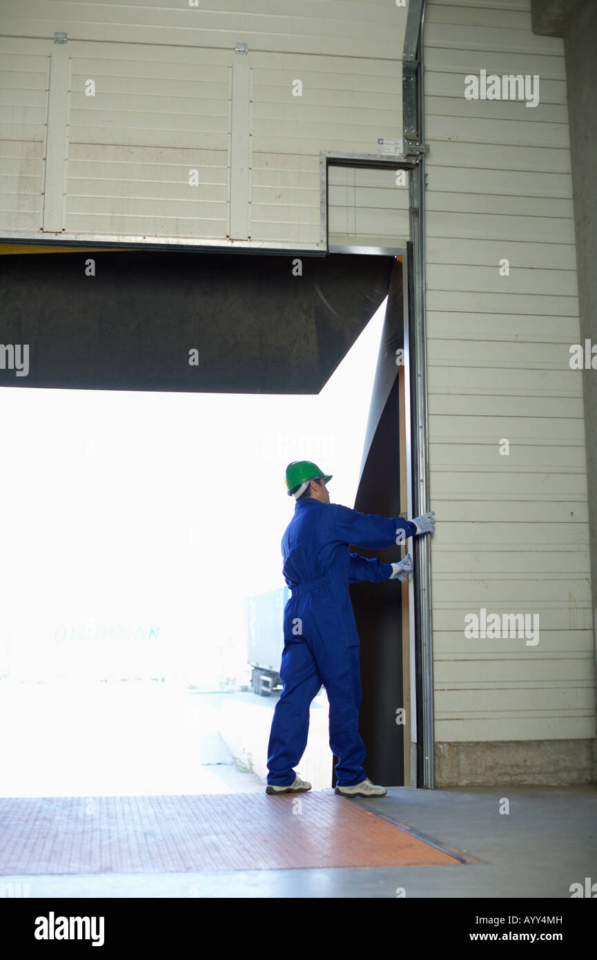 Man standing handling a roller shutter Stock Photo - Alamy