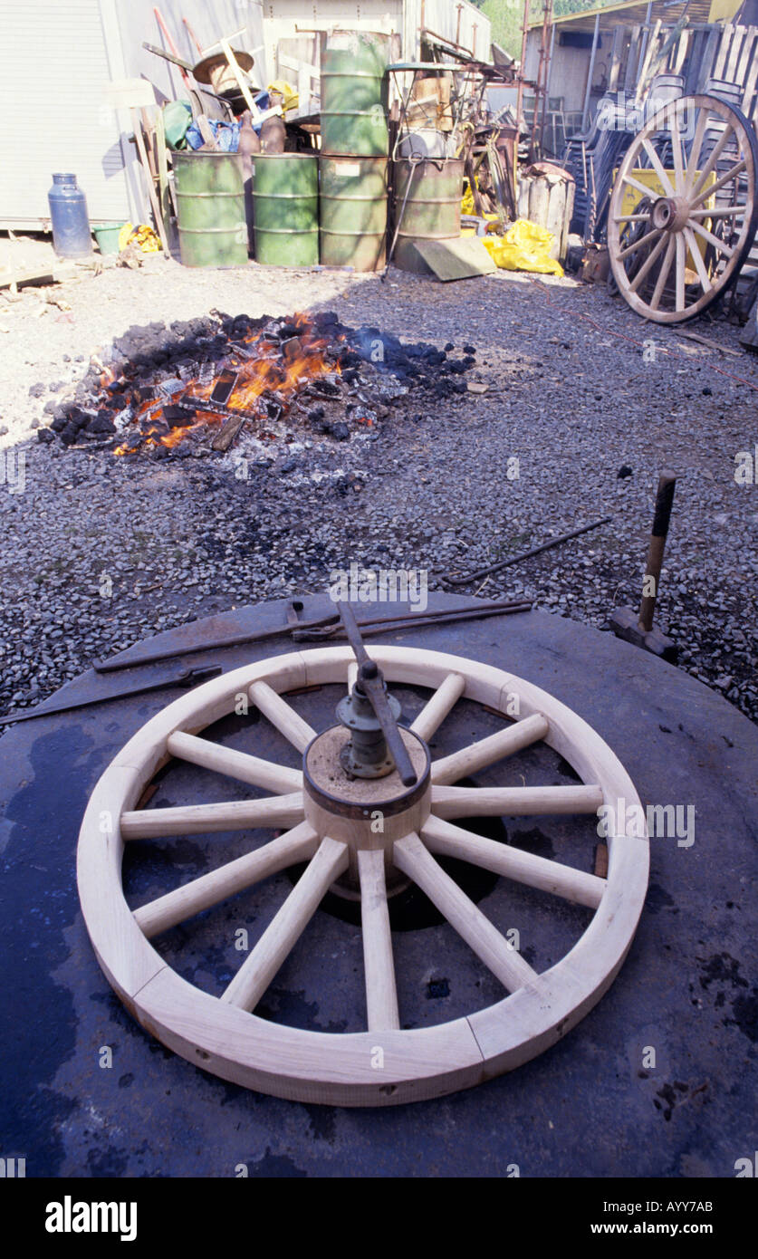 Tyring the wooden wheel the traditional way by fire to heat the outer ...
