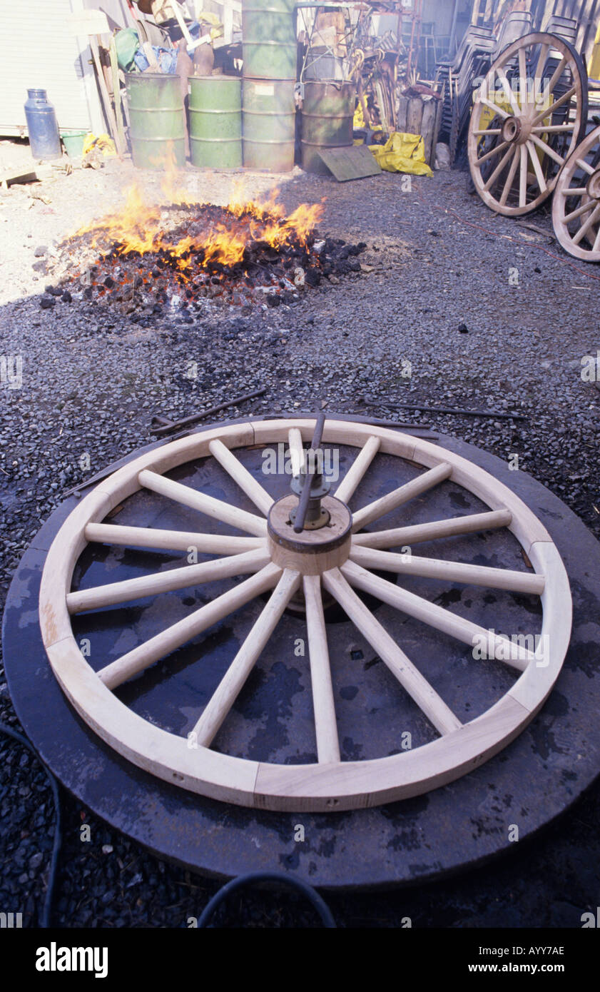 Tyring the wooden wheel the traditional way by fire to heat the outer ...