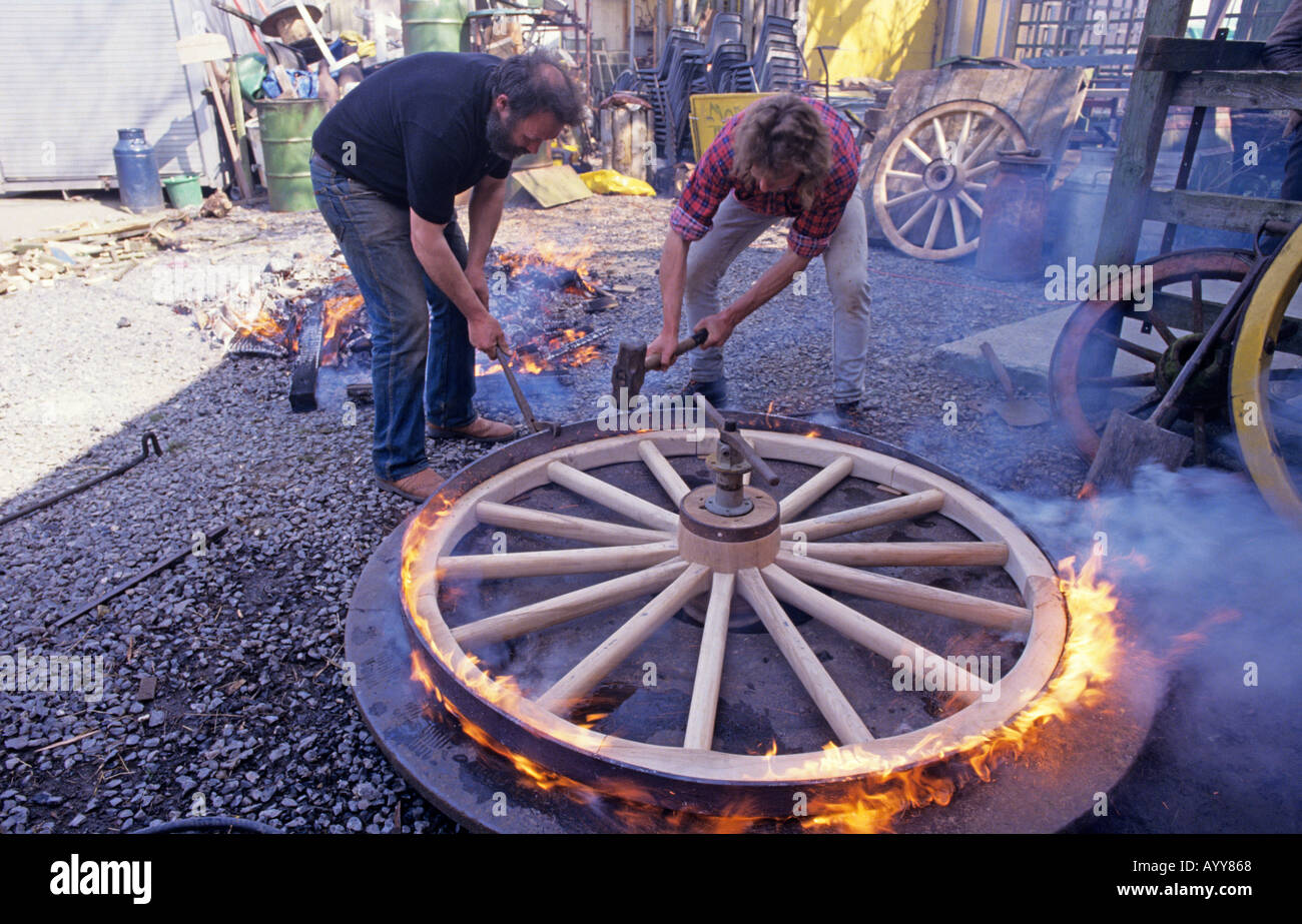 Wheelwright's at work ( tyring the wheel ) putting a metal hoop around ...