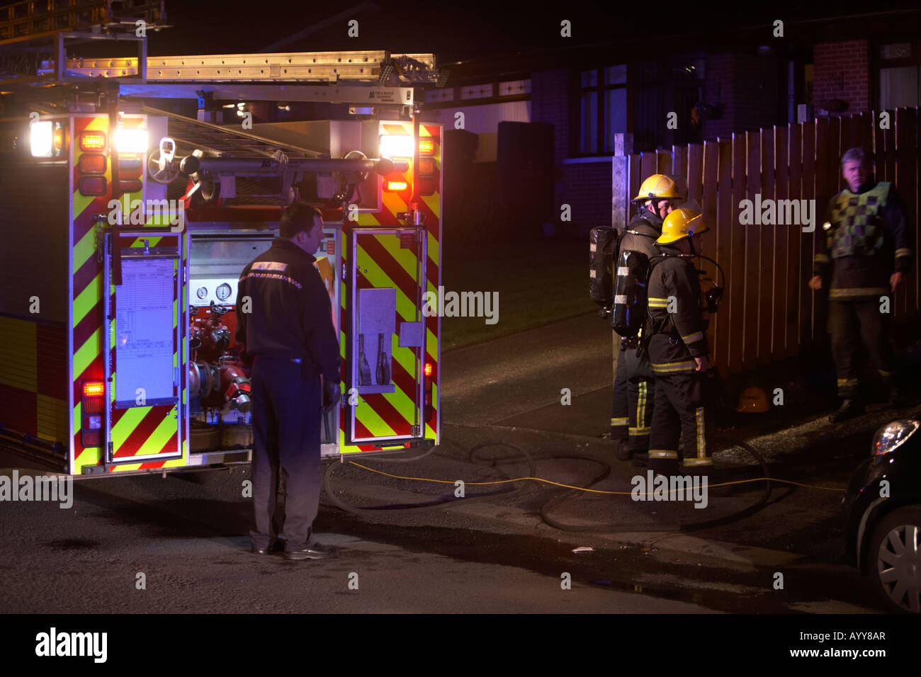 firefighters waiting behind a fire truck pumping engine at the scene of ...