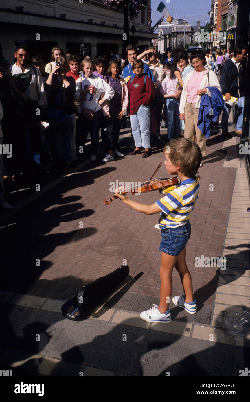 A small boy busking with his violin for an audience in Grafton Street ...
