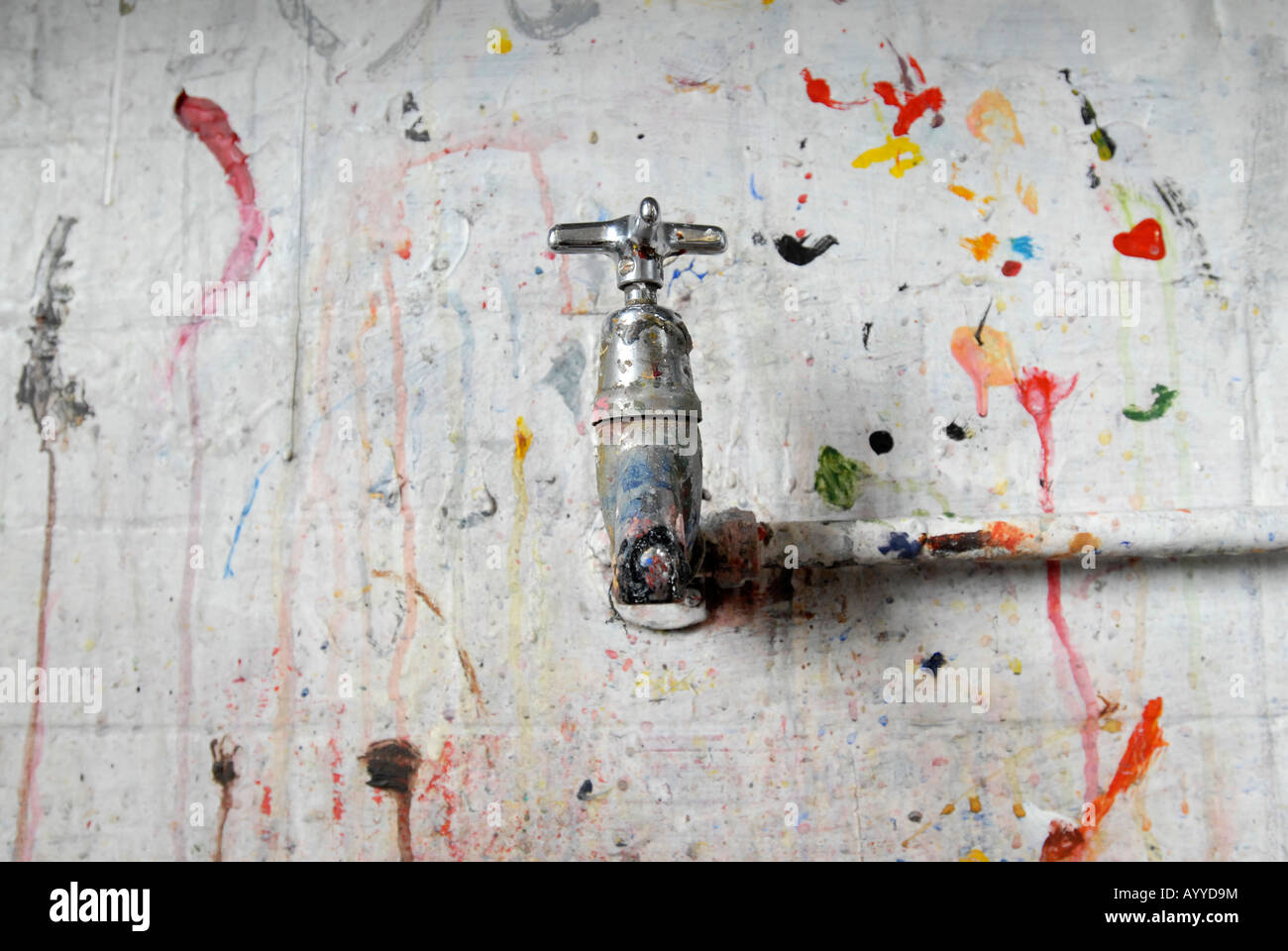 Paint-spattered water tap on the wall of an art classroom Stock Photo ...