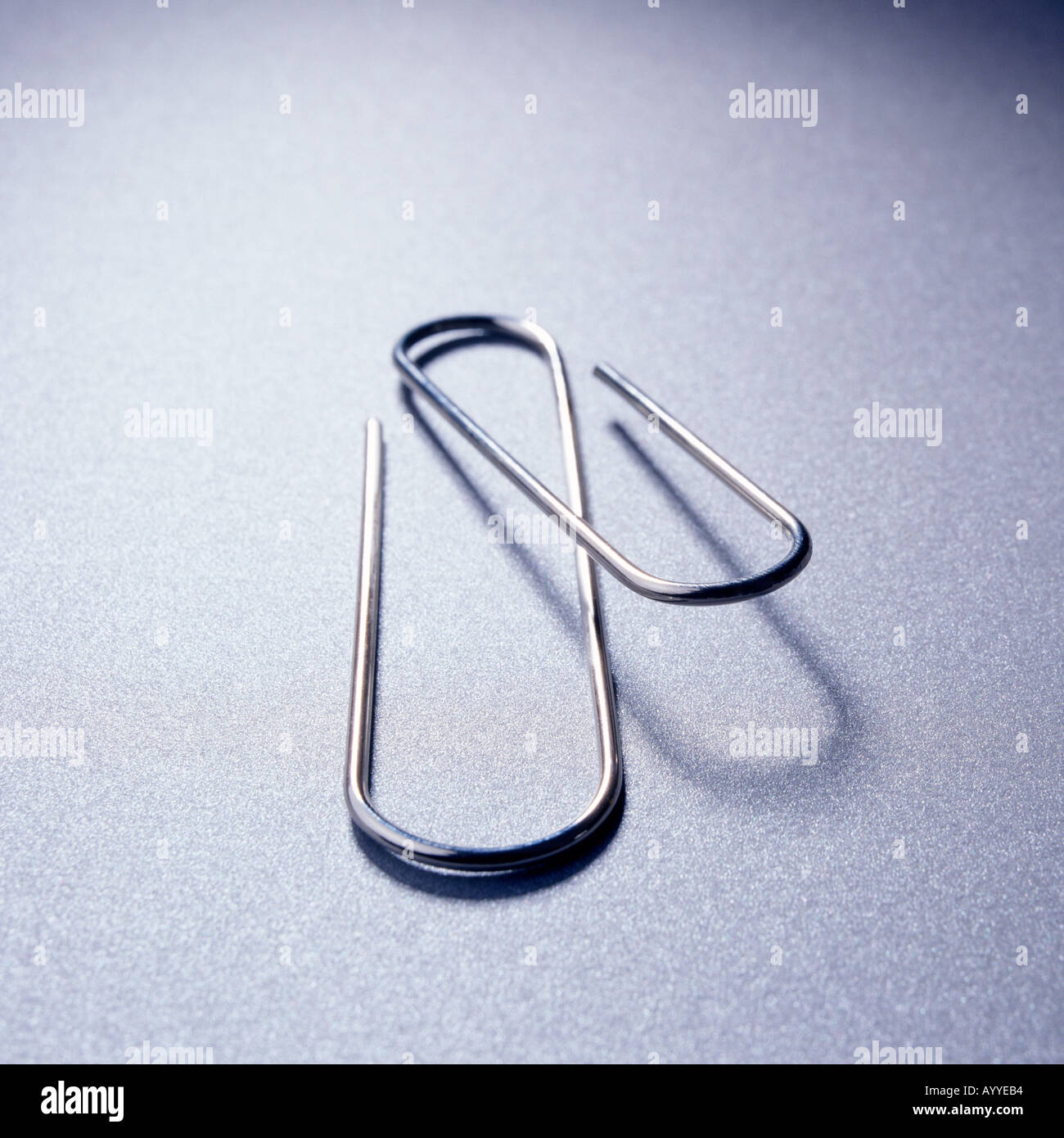 One large metal paper clip bent out of shape on light grey metallic ...