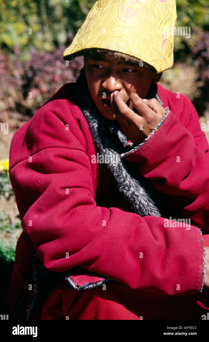 One Tibetan Buddhist monk wearing red robe and yellow hat touching his ...