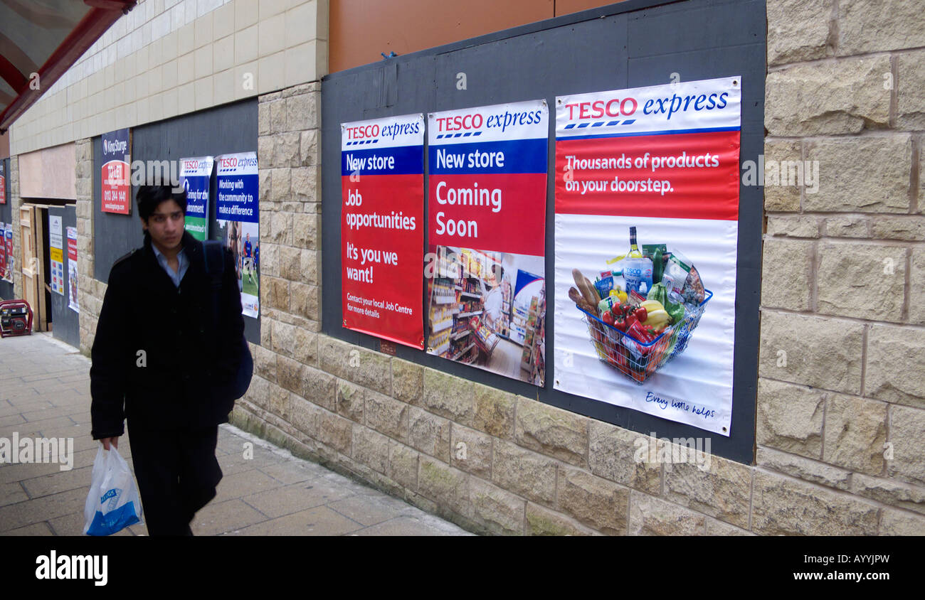 Man walking past signs advertising the opening of a Tesco Express store ...