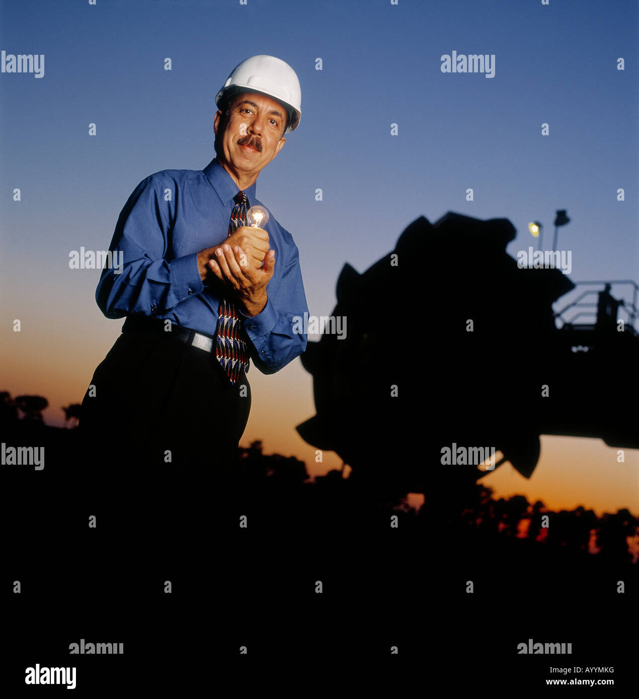 Power generation plant engineer holding glowing light bulb, with radial ...