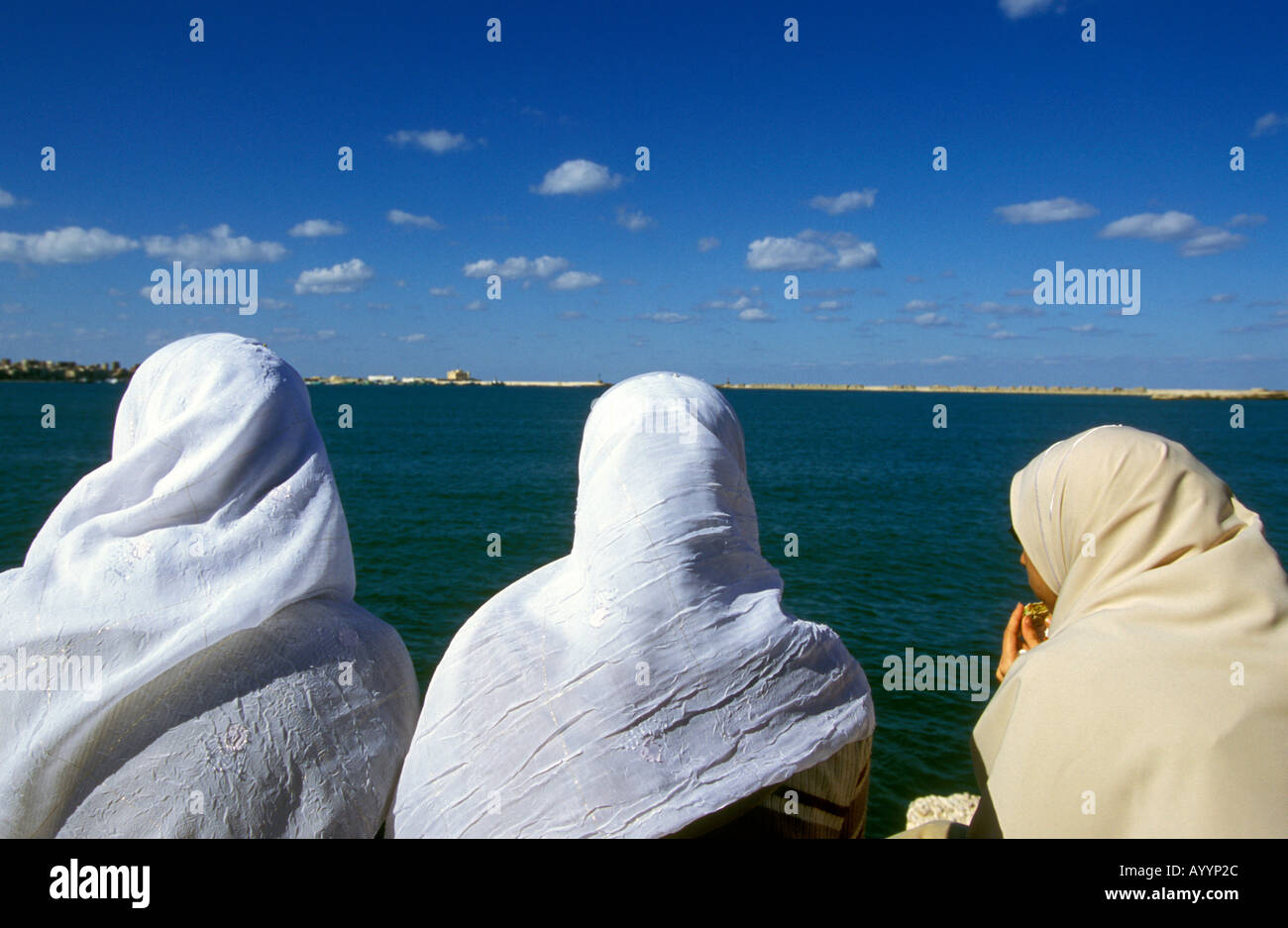 Three Muslim women in traditional dress looking out over the ...