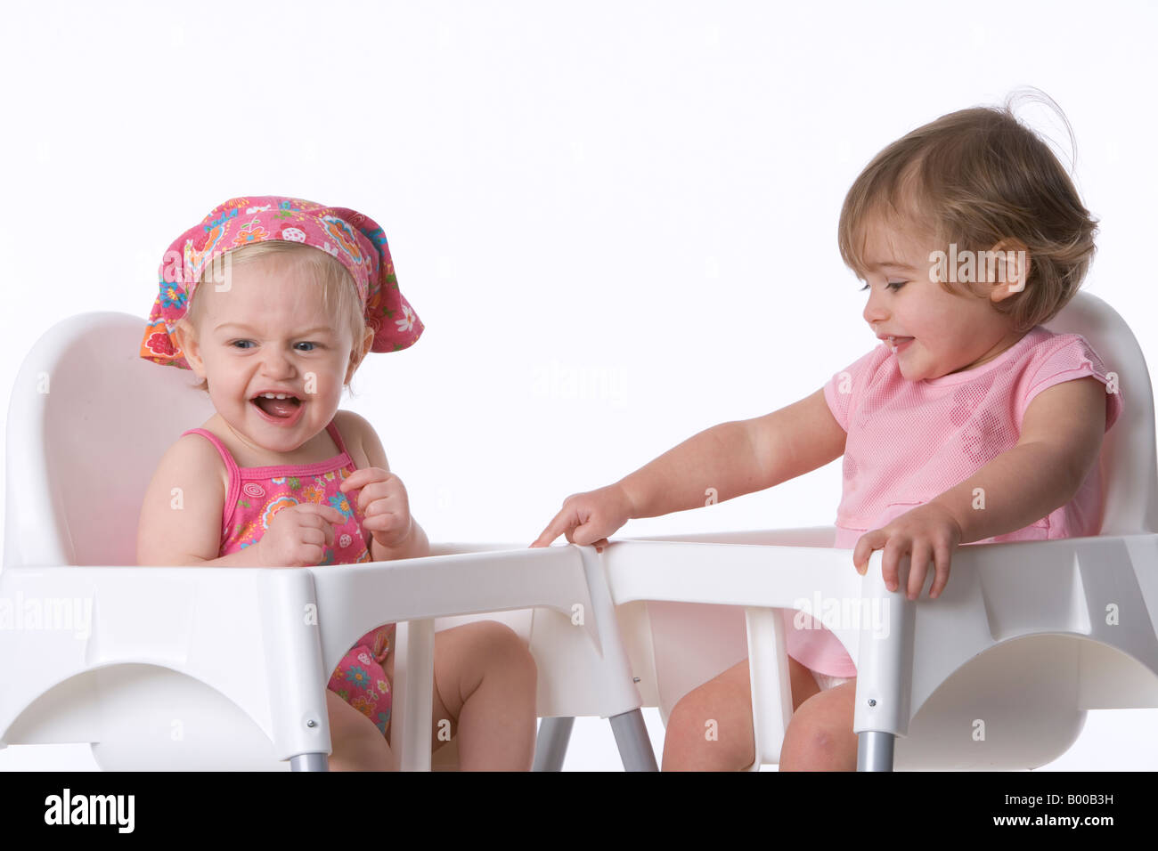 Two little girls in a baby chair Stock Photo - Alamy
