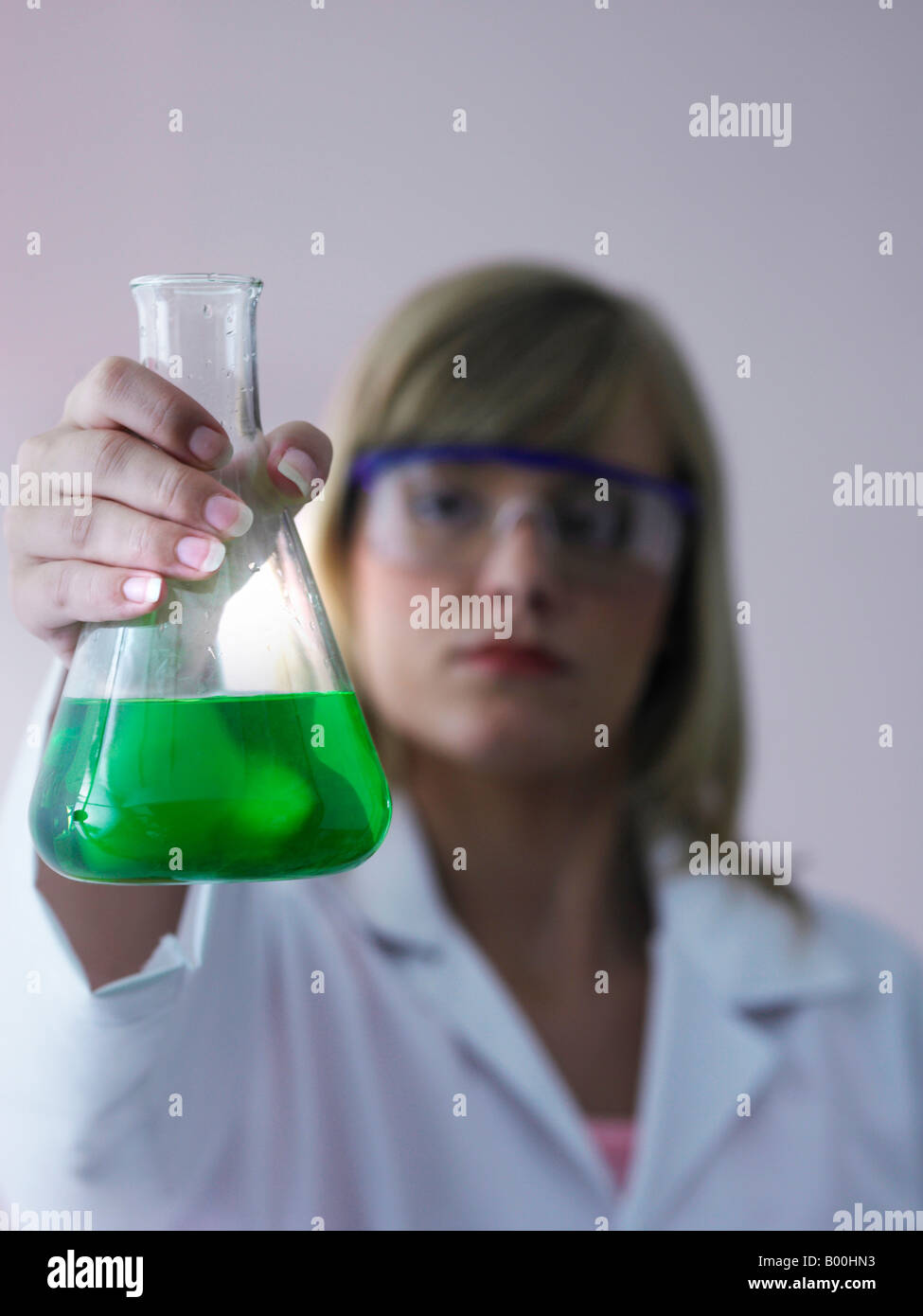 scientist holding a green color solution in a container Stock Photo - Alamy