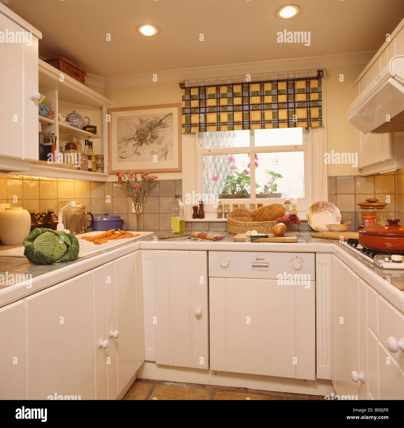 Yellow and grey checked blind in small fitted cream kitchen with ...
