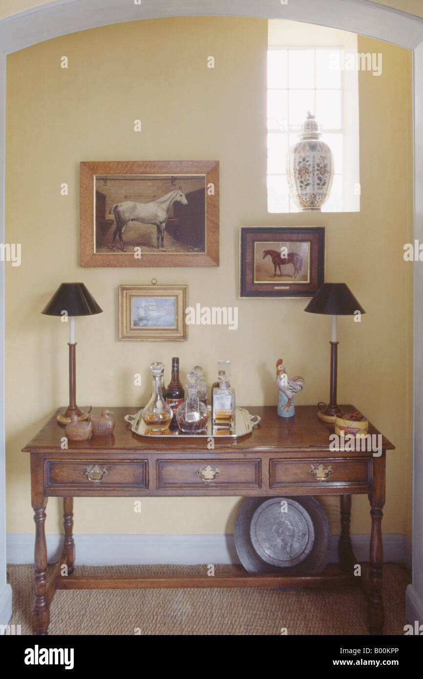 Pictures above lamps and drinks tray on antique table in diningroom ...