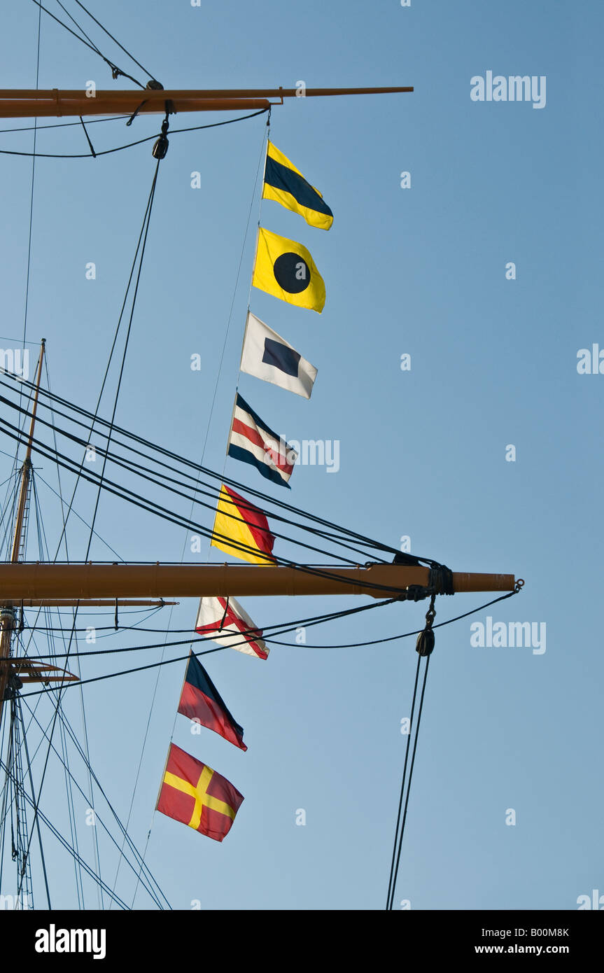 Signal flags flying from the mast of a sailing ship, against the blue ...