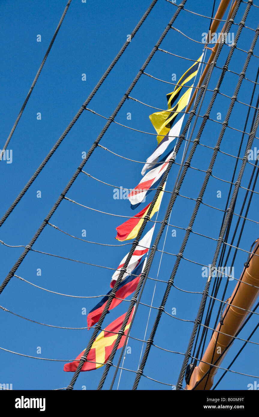 Signal flags flying from the mast of a sailing ship, against the blue ...