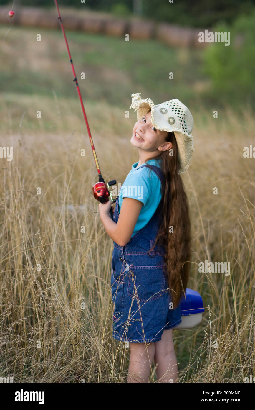 Young girl carrying a fishing pole and tackle box Stock Photo - Alamy