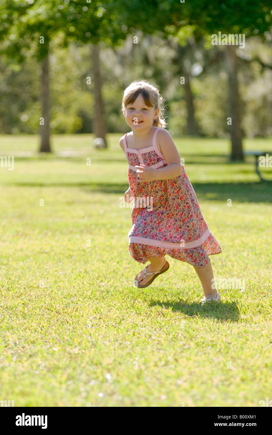 Happy 4 year old girl running in park side stepping happy bright smile ...