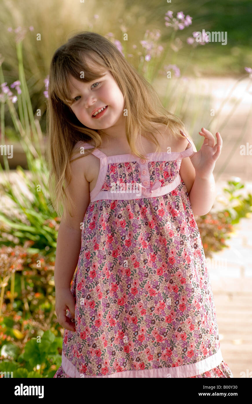 4 year old little girl in pink print flower dress in park with joyful ...