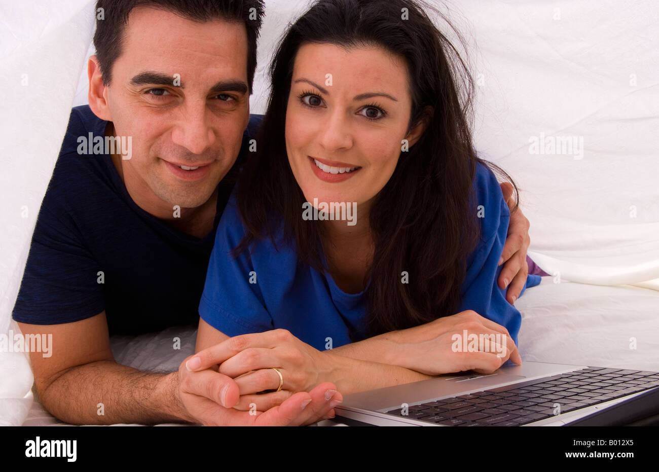 Dating couple happy together on internet computer even in bed under ...