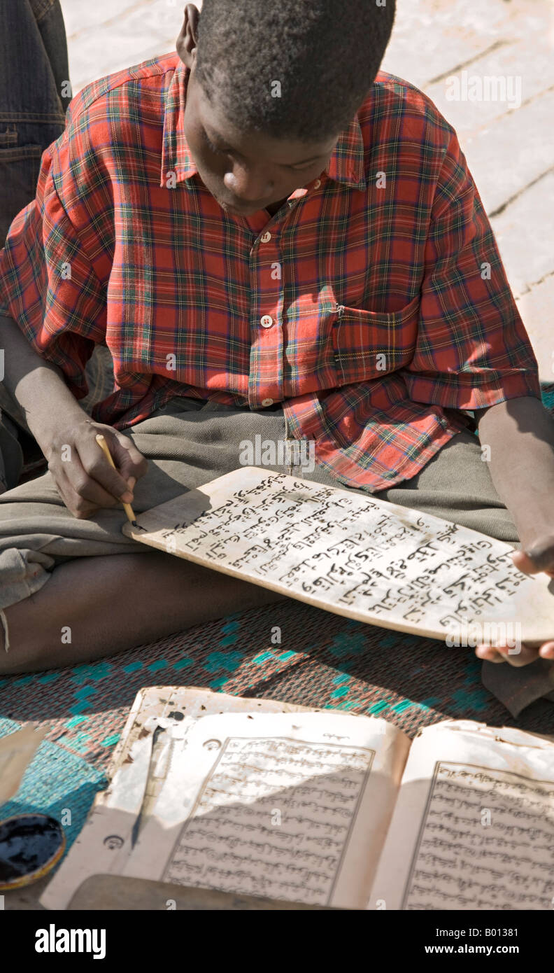 Mali, Timbuktu. A young boy copies Arabic on a wooden 'slate' in ...