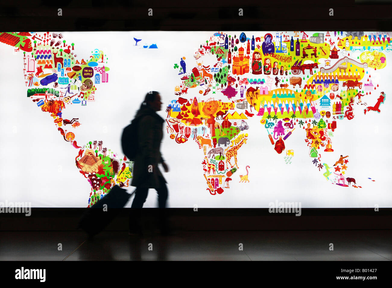 Traveller walks past a colourful map of the world at Linate Airport ...