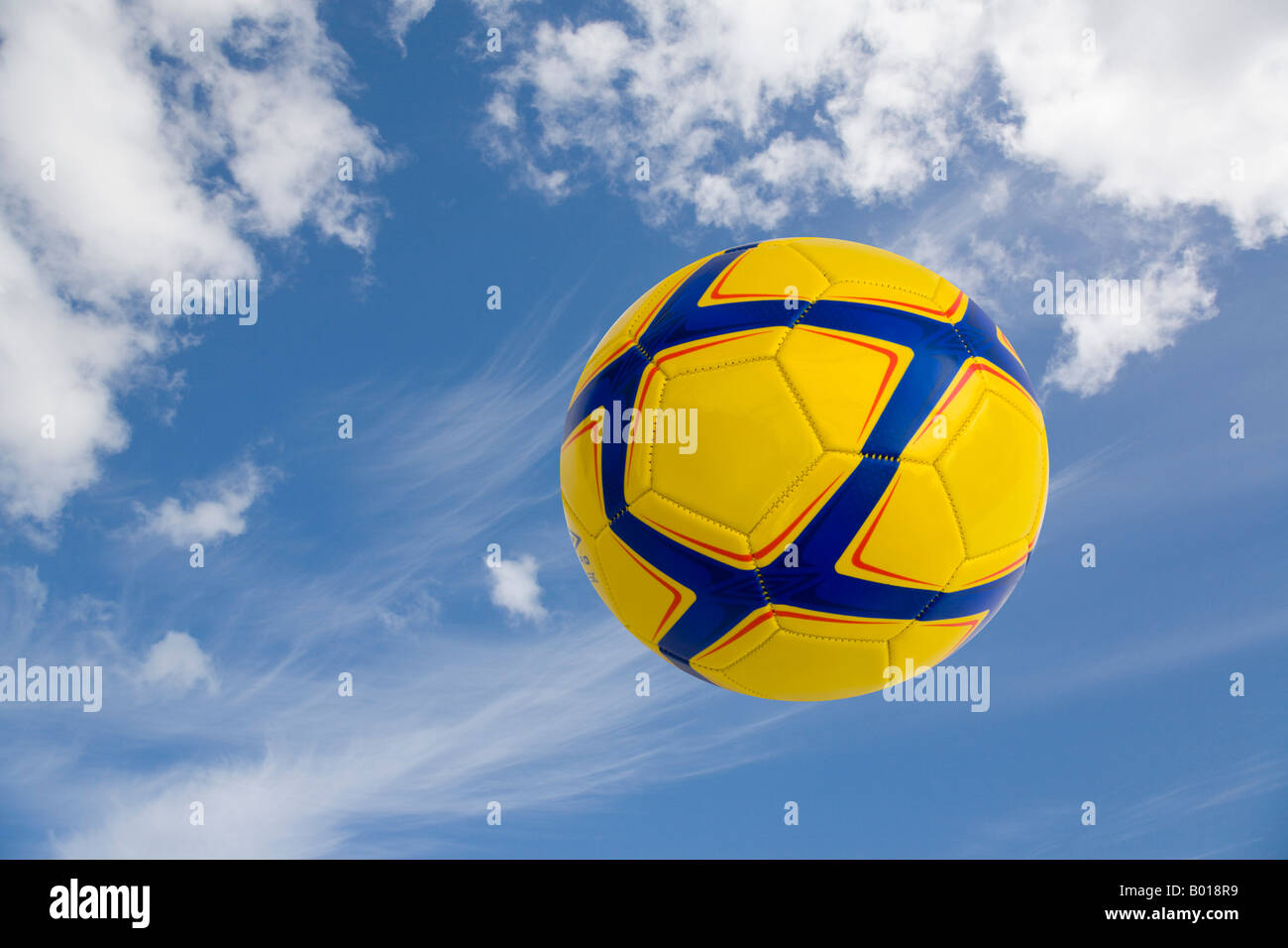 Yellow and blue football flying across blue sky with clouds Stock Photo ...