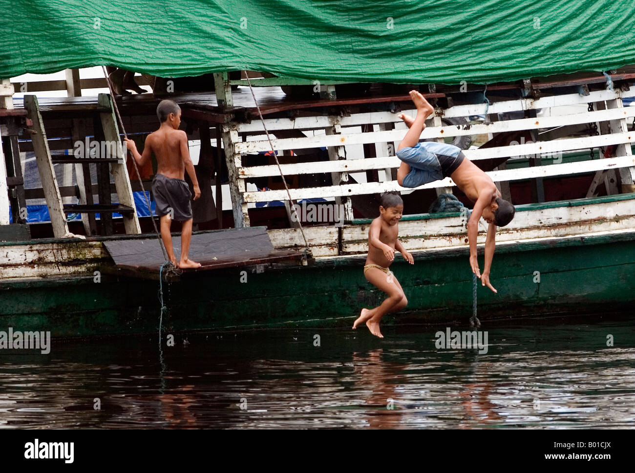 Boys diving from their boat into the river Negro Stock Photo - Alamy
