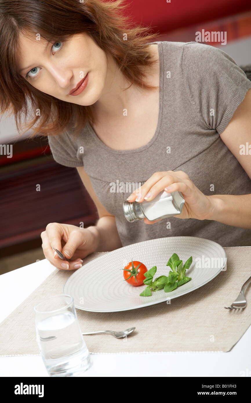Young woman salting her plate Stock Photo - Alamy