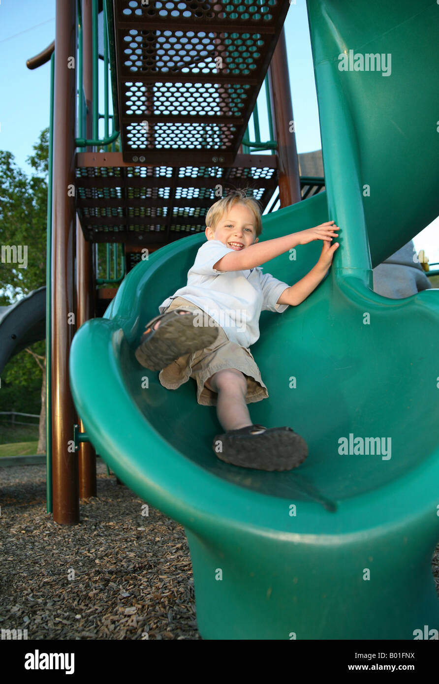 happy young boy sliding down a playground slide towards camera Stock ...
