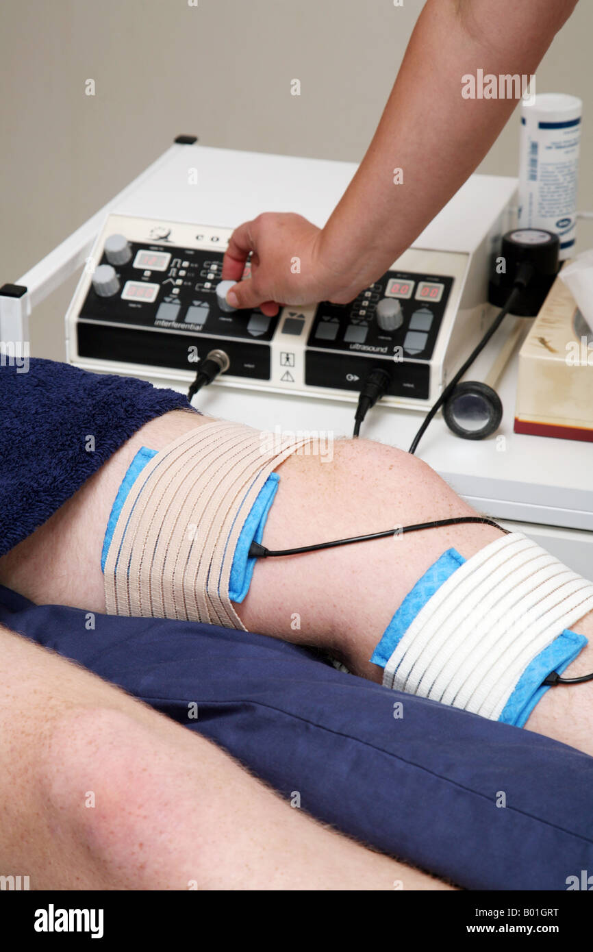 A physiotherapist applies Interferential therapy to a patient's knee ...