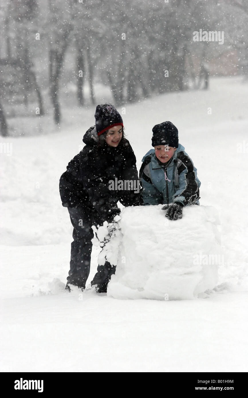 Children rolling snowball snowman hi-res stock photography and images ...