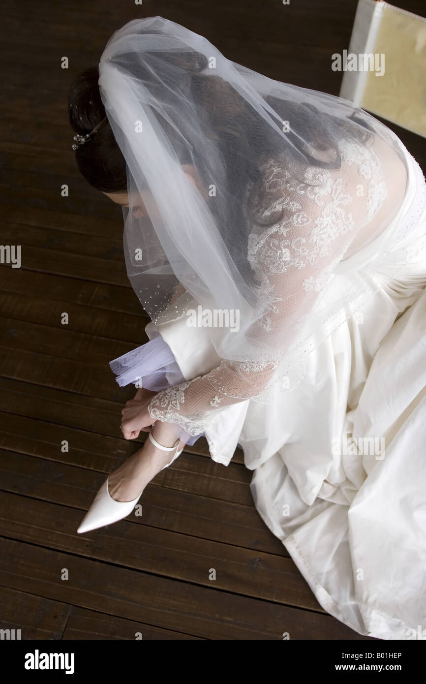 Bride sitting on the chair putting the shoes on Stock Photo - Alamy