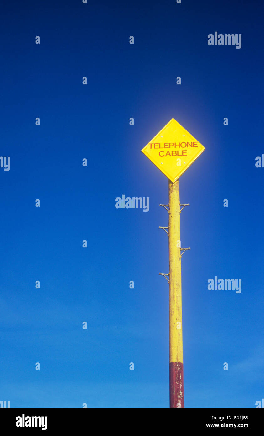 Telephone pole painted yellow and red with diamond shaped yellow sign ...