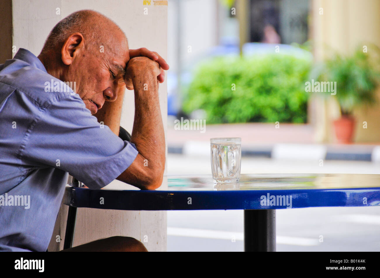 Older Asian man sitting down at empty table in restaurant in Singapore ...