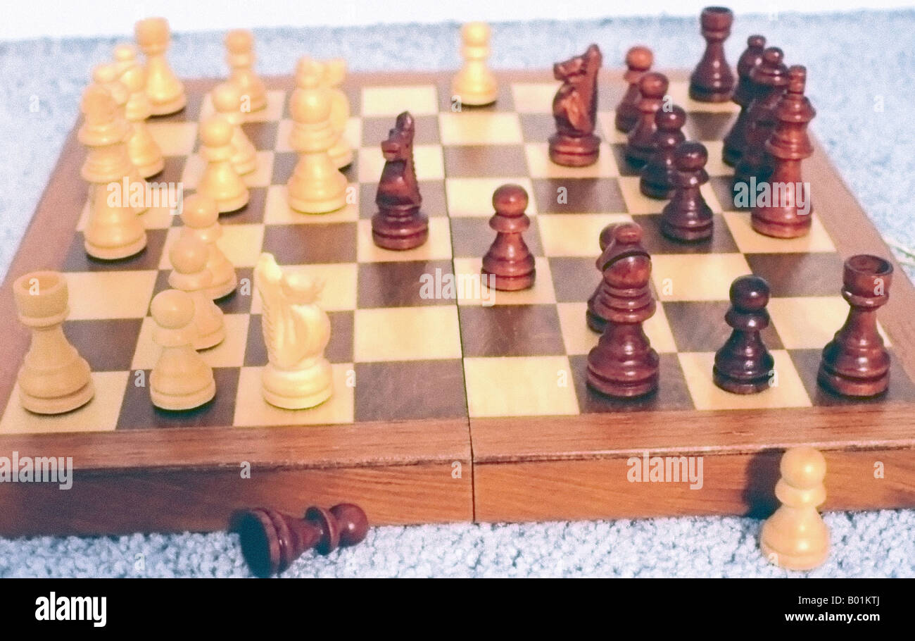 A full view of a carved, all wood, chess board. A game in progress, the ...