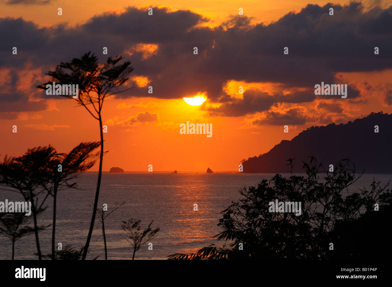 Sun behind clouds setting over the Pacific Ocean at Carate Costa Rica ...