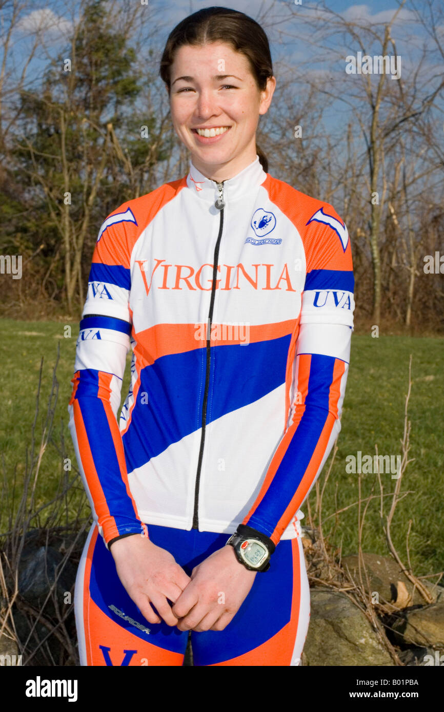 Portrait of college aged young female cyclist standing with bike ...