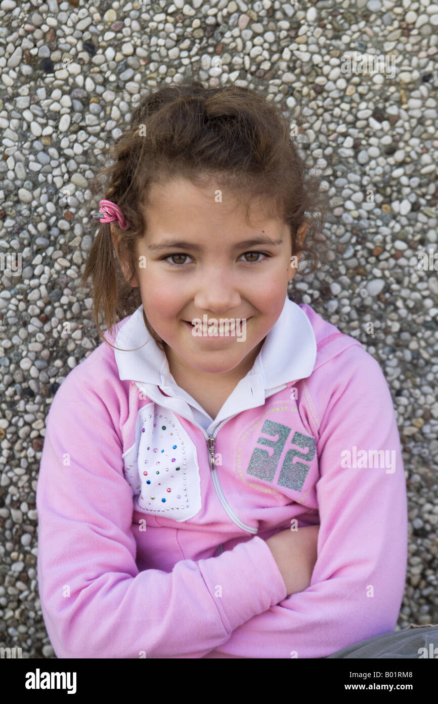 Smiling child with crossed arms against a grey wall Stock Photo - Alamy