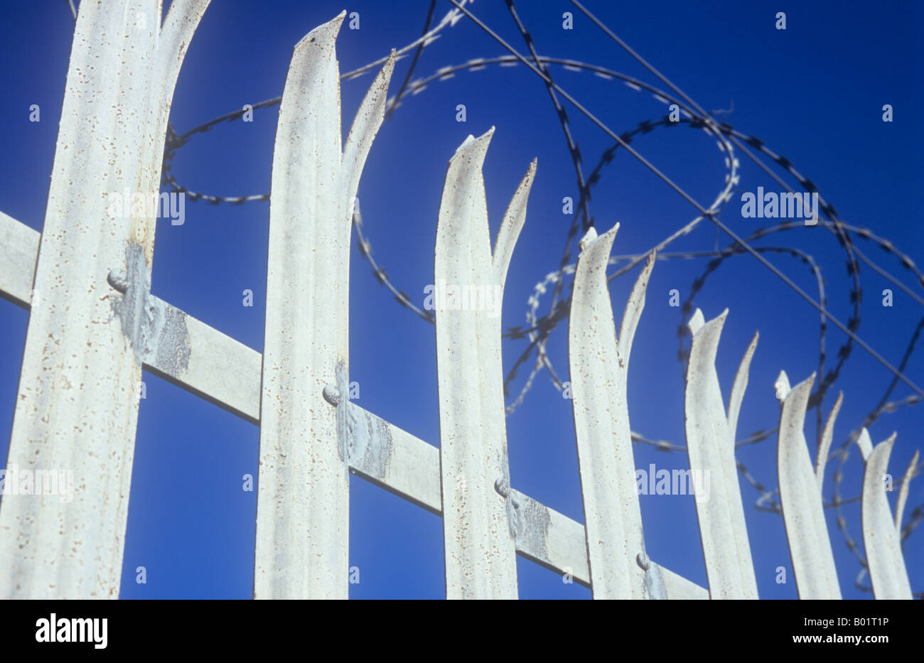 Detail of metal security railings topped with angled spikes and razor ...