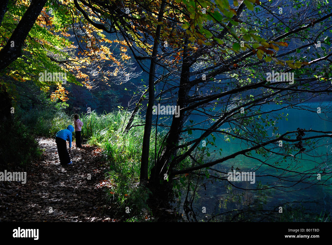 Two children walking on path beside lake with autumn leaves. Plitvice ...