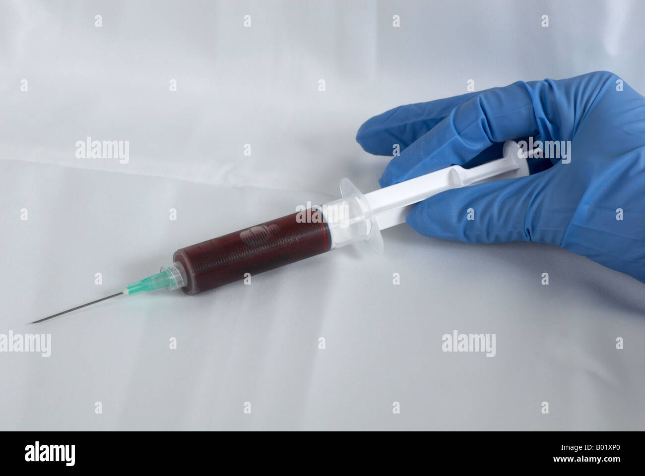 Blood in a syringe being held by surgical gloved hand Stock Photo - Alamy