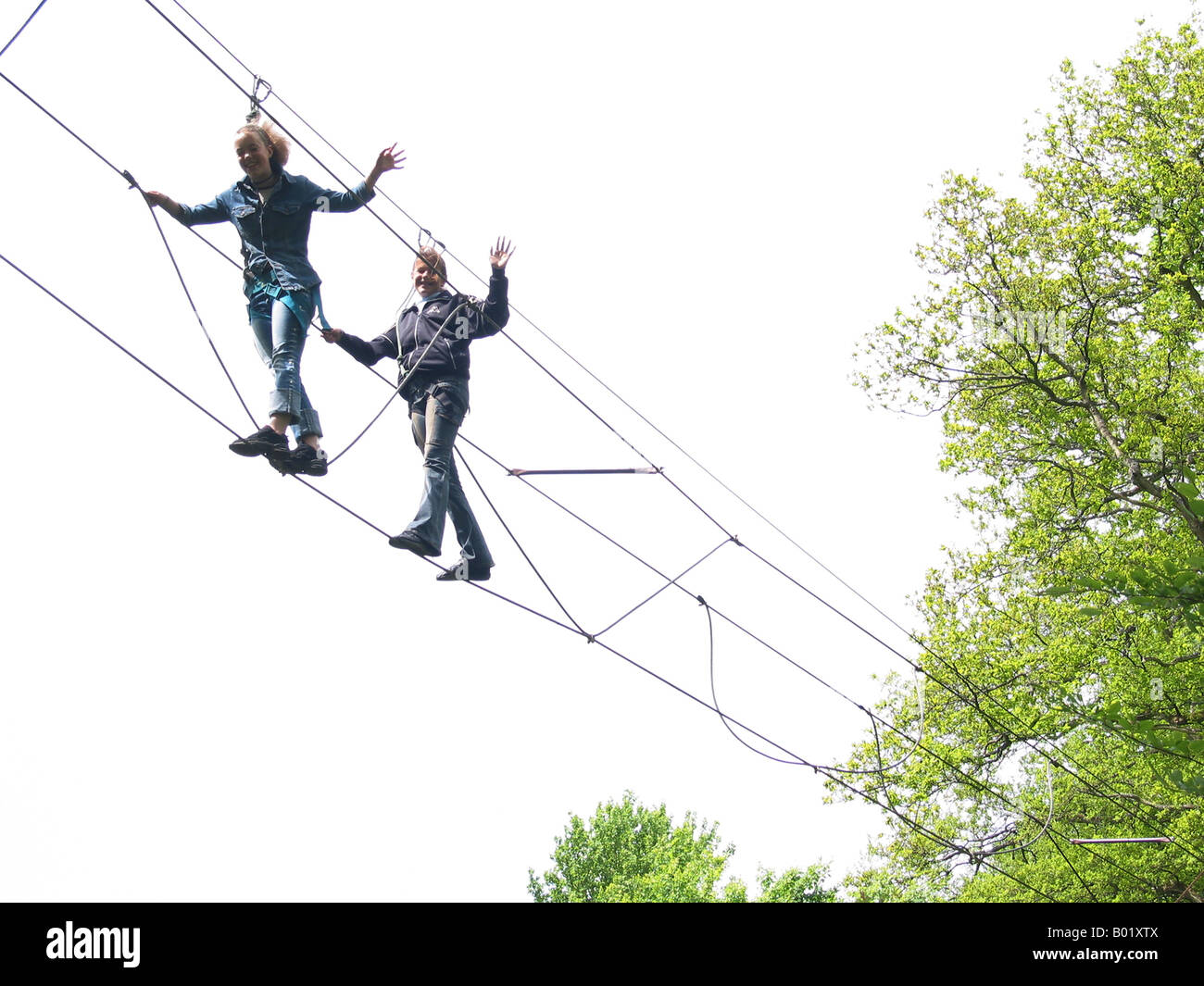 two teenagers walking over rope bridge on survival trip Stock Photo - Alamy