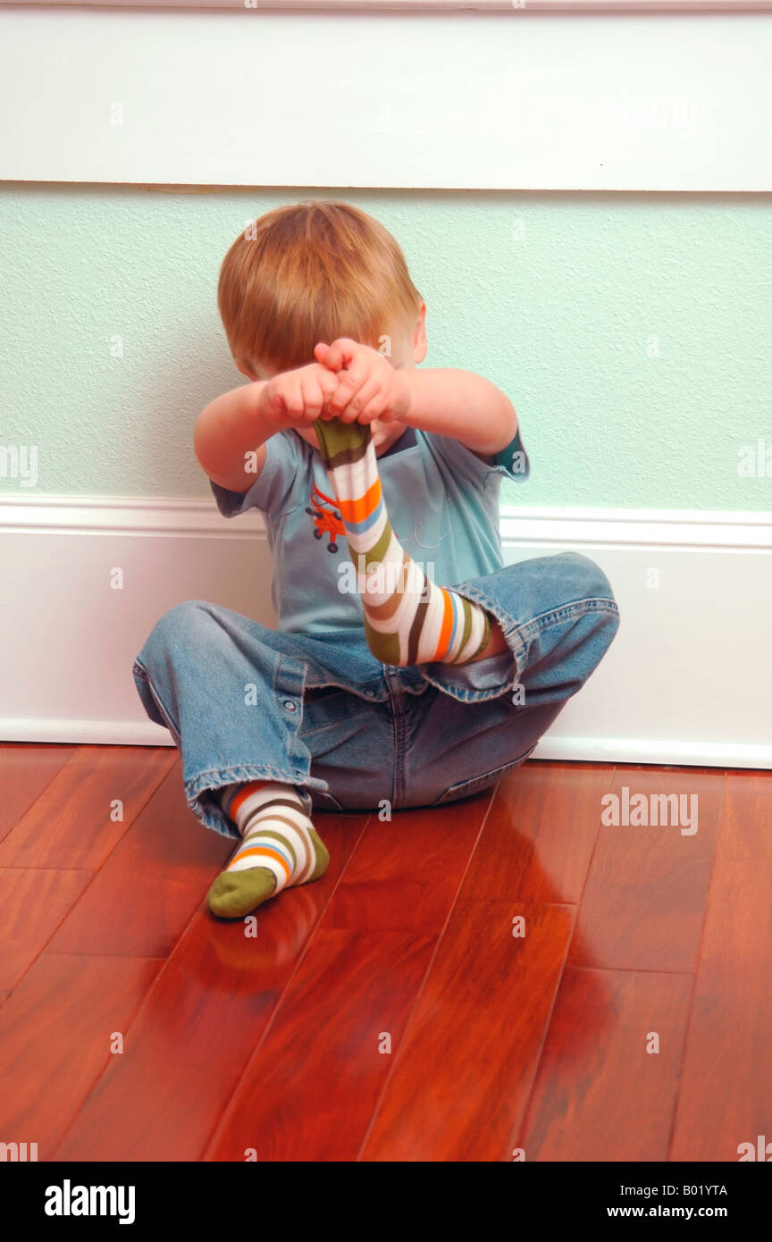 Little boy trying to remove his sock Stock Photo - Alamy