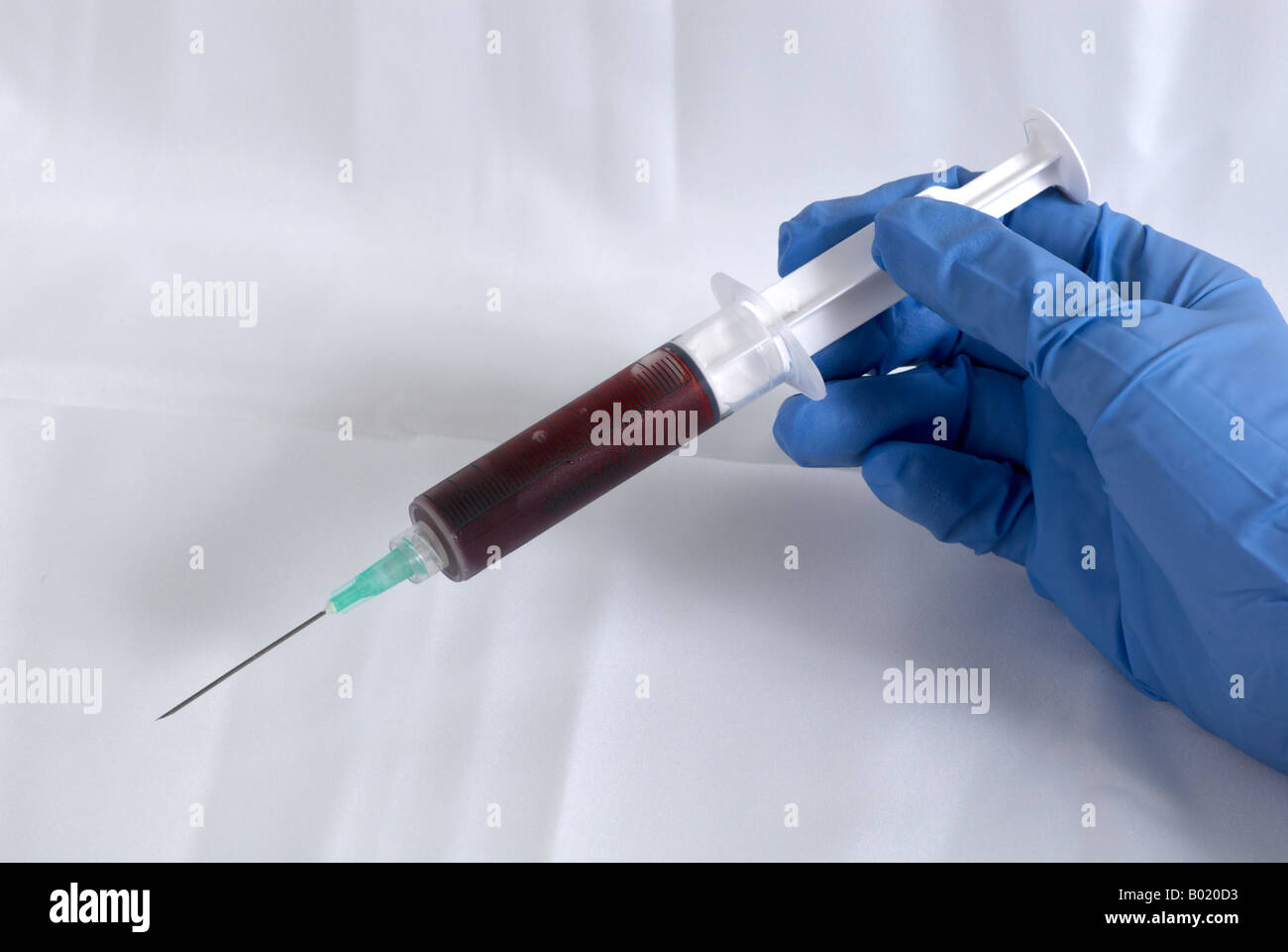 Blood in a syringe being held by surgical gloved hand Stock Photo - Alamy