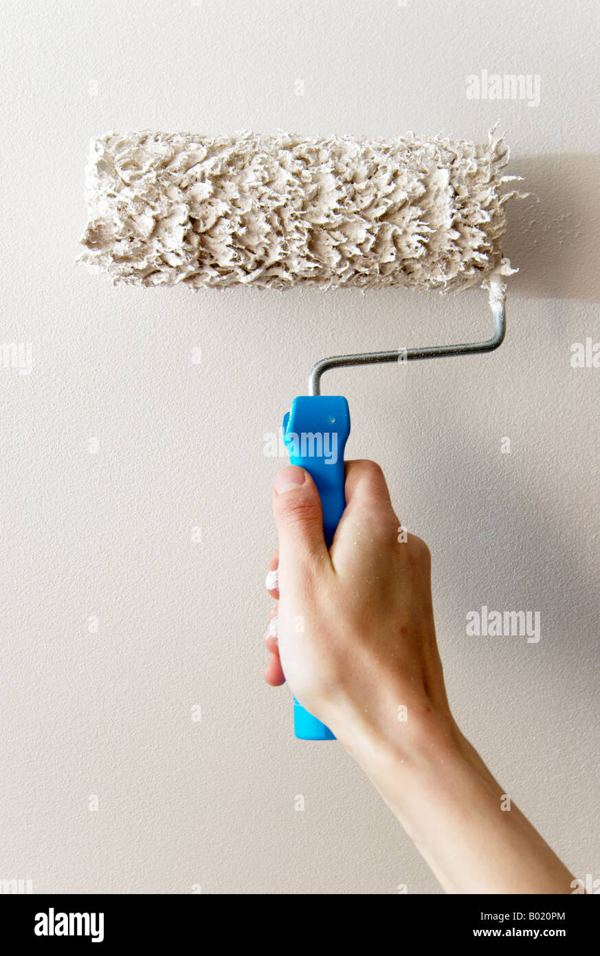 Hand, paint-roller and fresh paint on white wall with nice surface ...