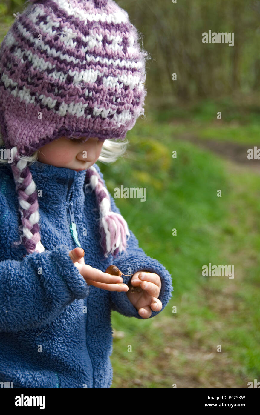 Stock photo of a little girl in a hat studying a slug in her hand Stock ...