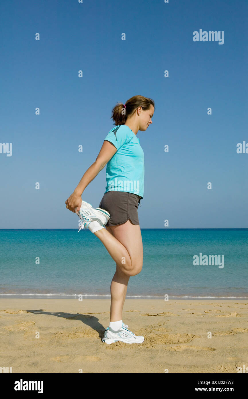 young woman doing stretching exercises on beach Stock Photo - Alamy