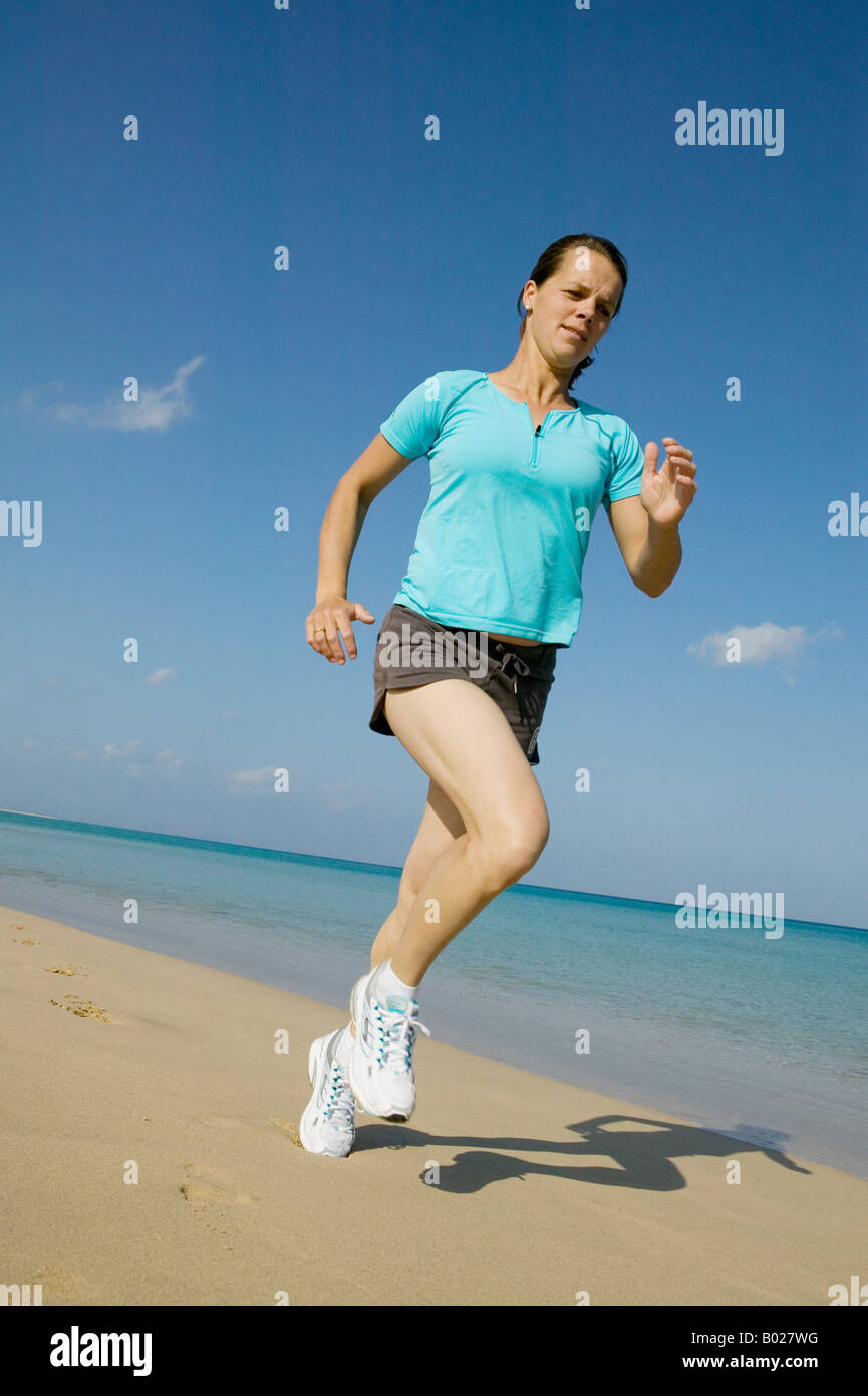 full body portrait of young woman jogging on beach Stock Photo - Alamy